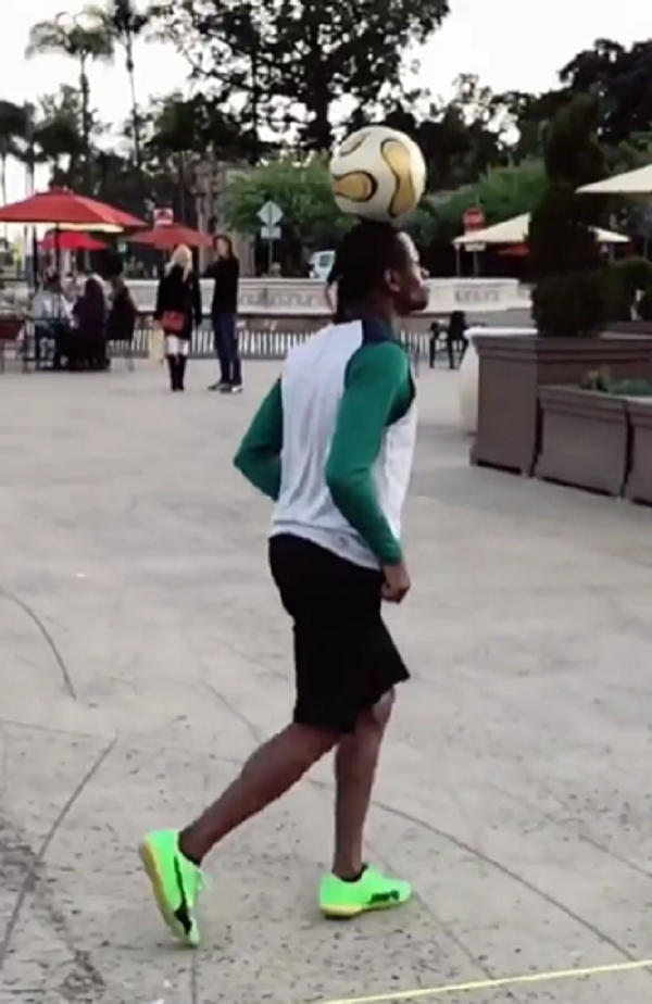 Man Balancing A Football On His Head While Moonwalking