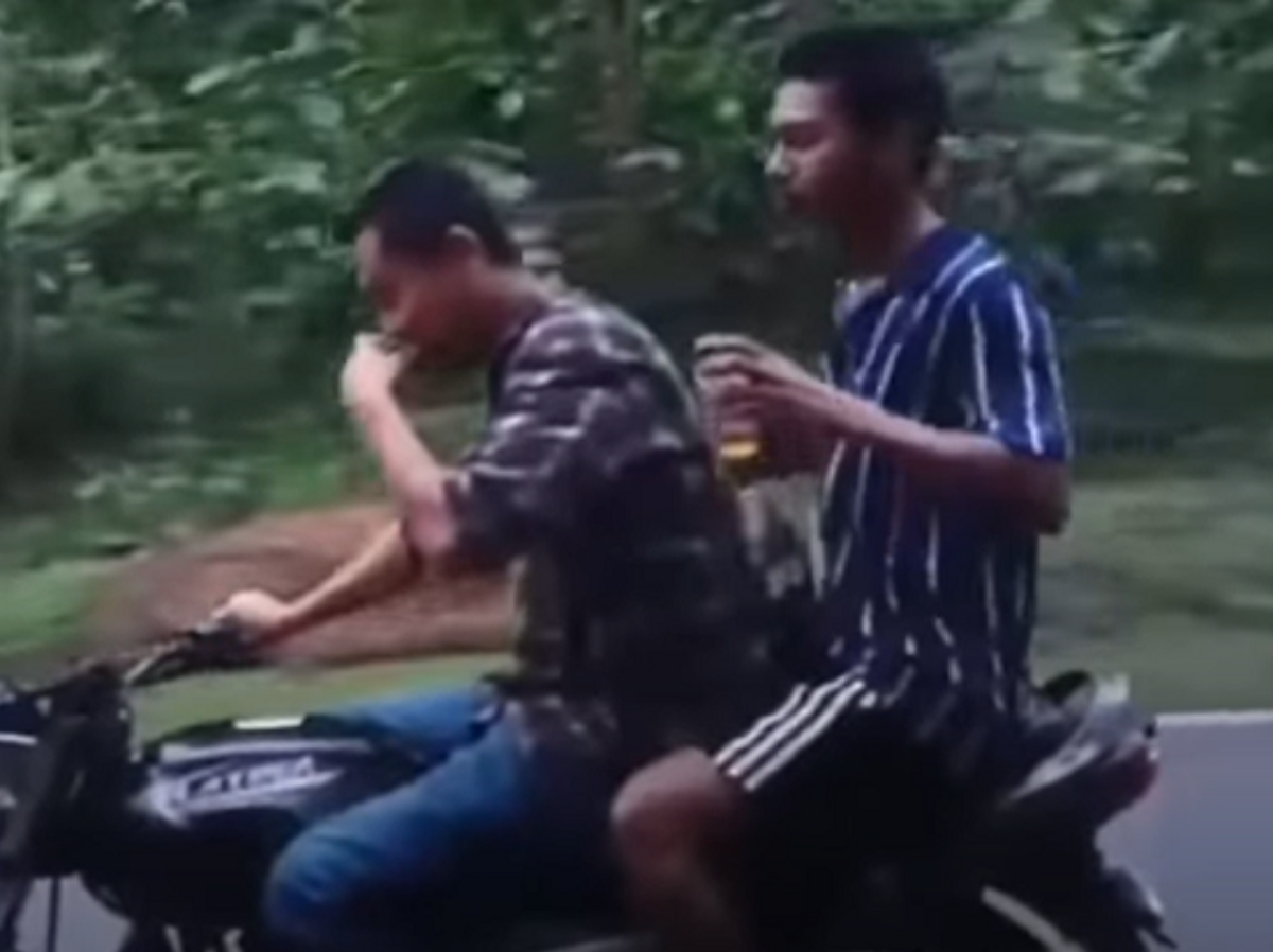 Two Men Drink Alcohol While Performing Stunts On Bike